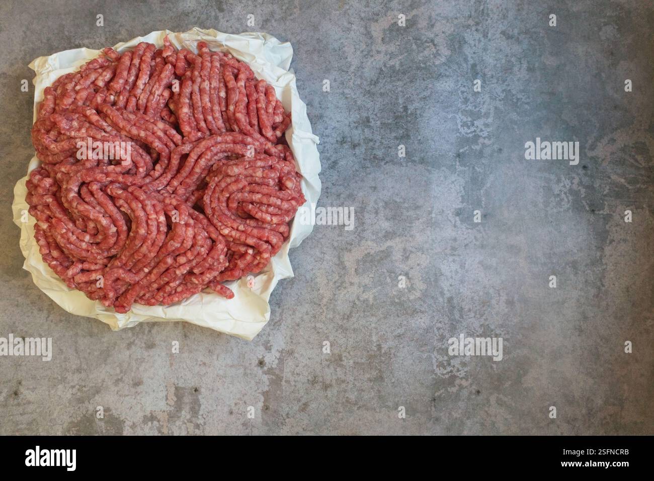 A piece of freshly minced beef placed on paper atop a concrete table ...