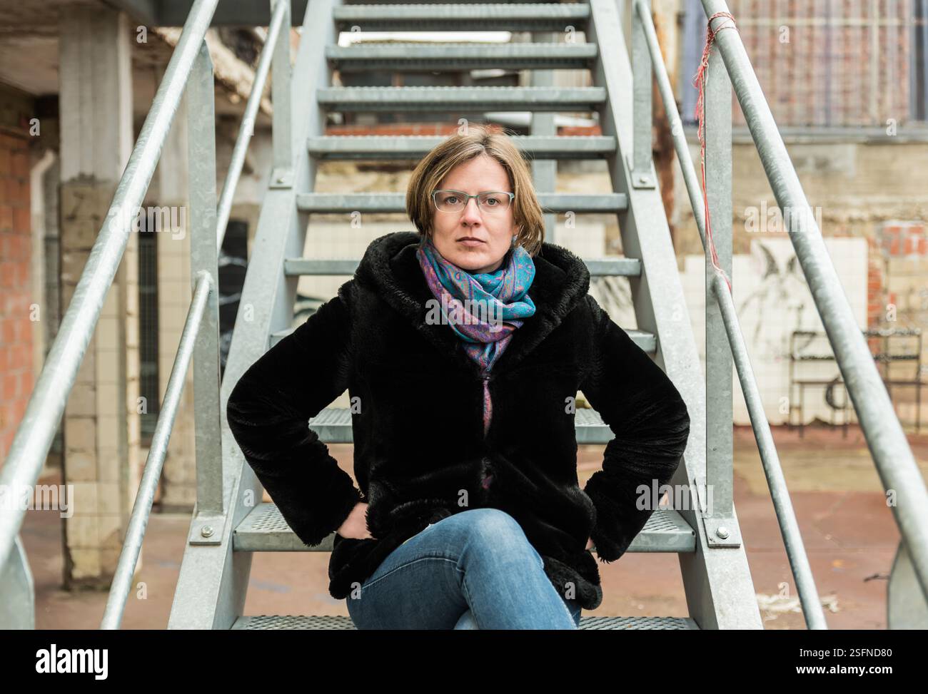 Outdoor portrait of a 33 yo white woman on a grungy inner court ...