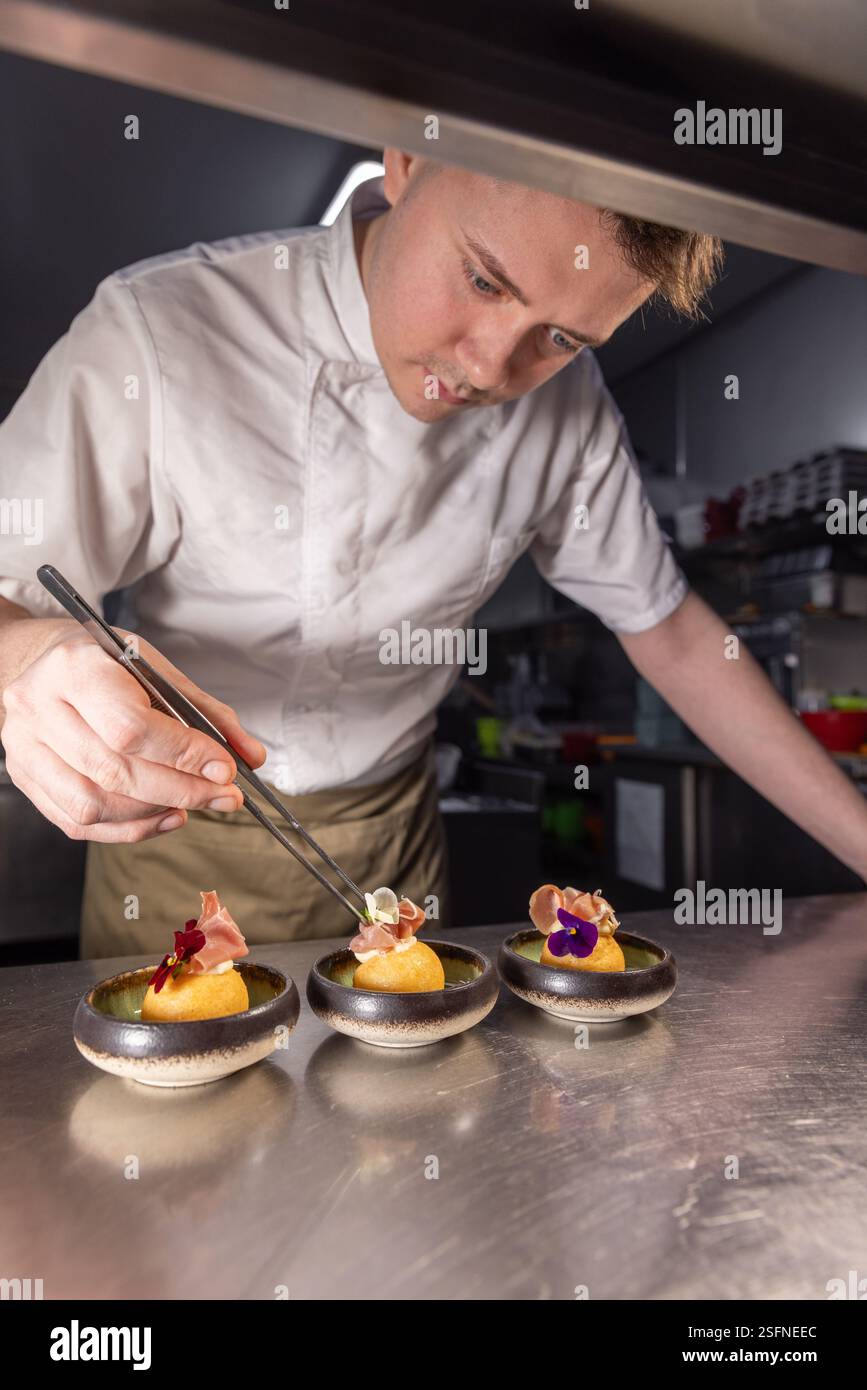 Professional chef carefully placing edible flowers and prosciutto on ...