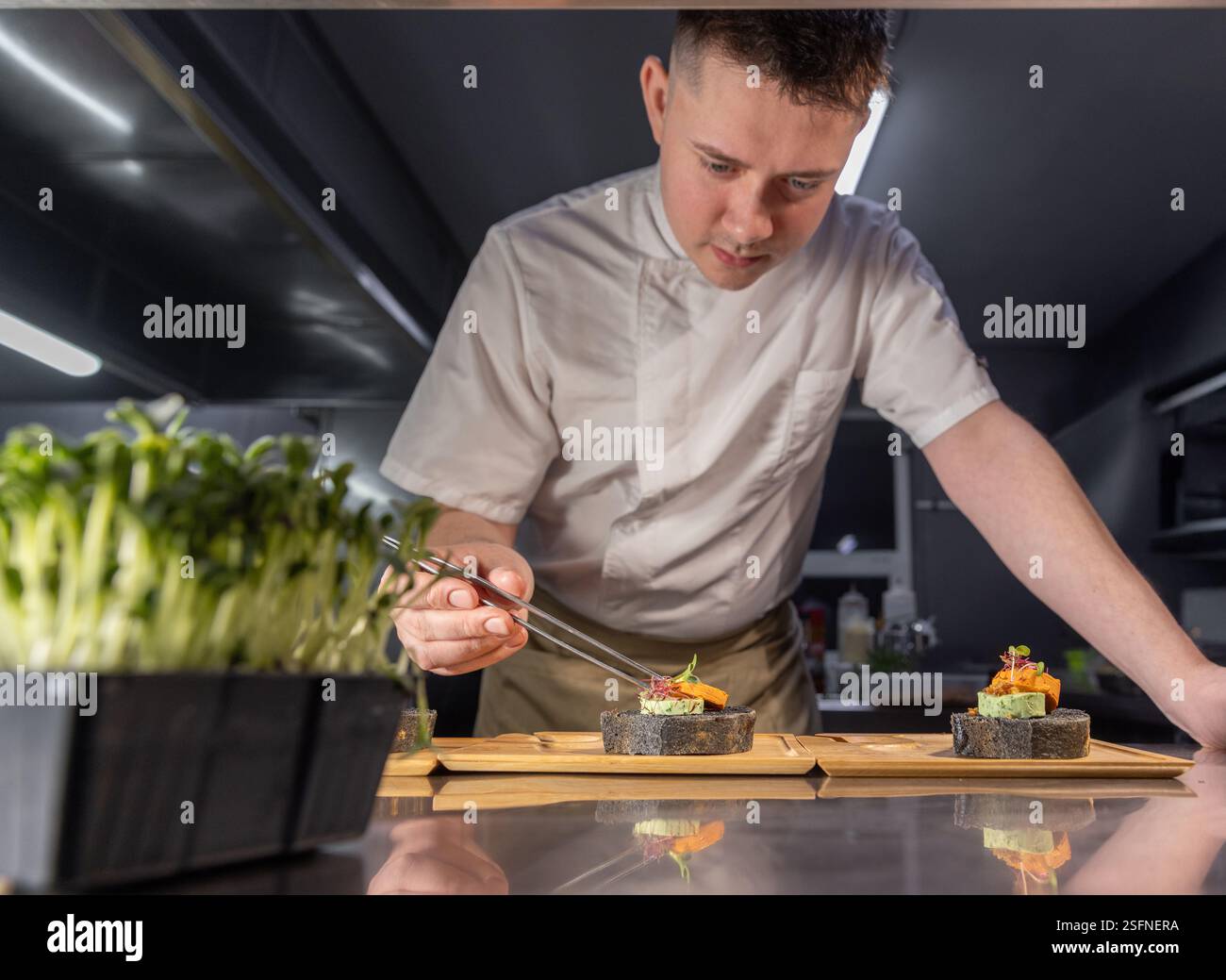 Professional chef carefully preparing gourmet black bread canapes ...