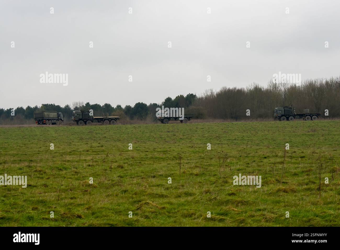 convoy of British army Heavy Utility Trucks driving along a dirt track ...