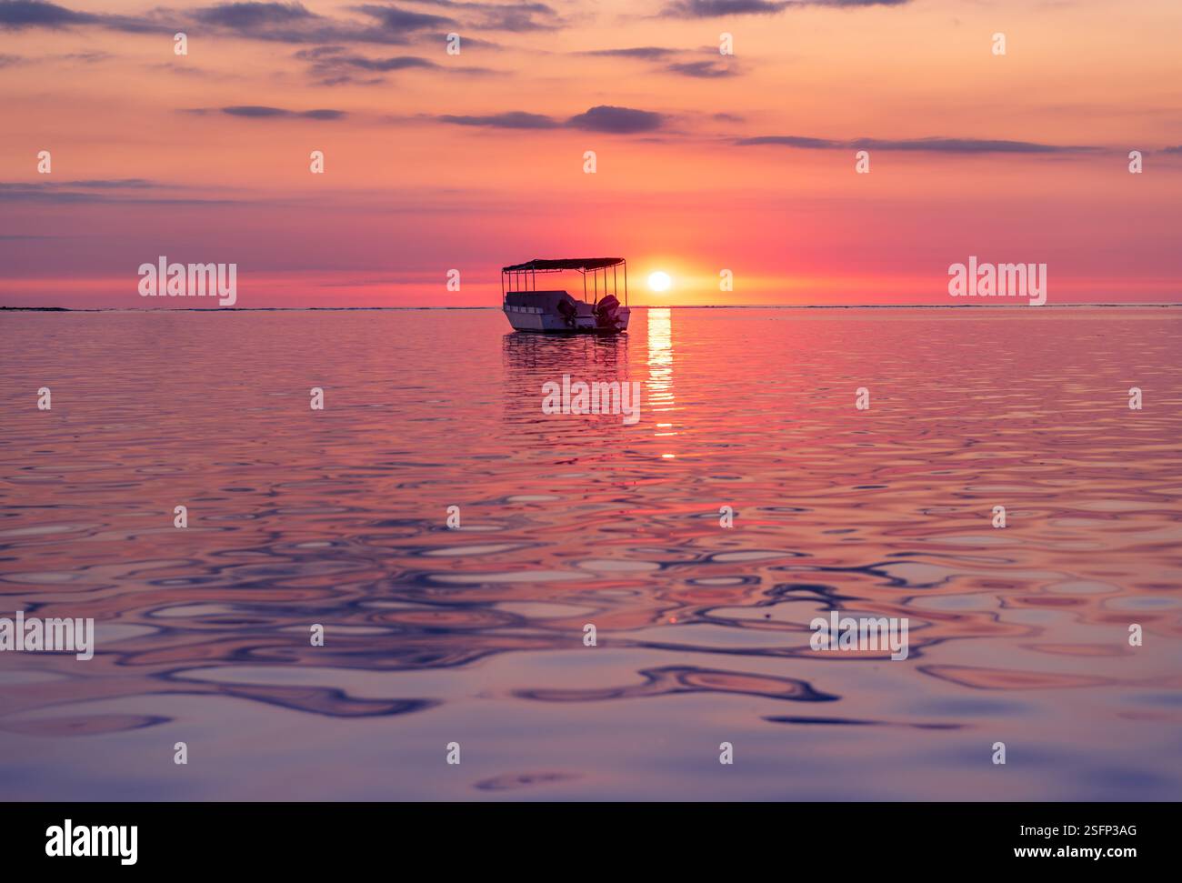 Touristic speedboat floating quietly in front of the sunset, Mauritius ...