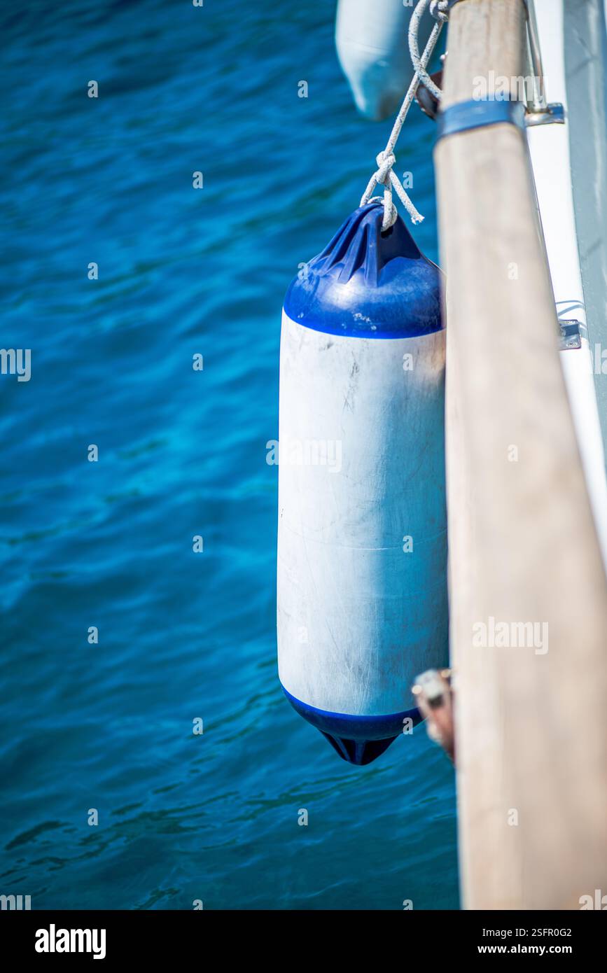 A close-up view of a fender hanging from a ship, secured with a sturdy ...