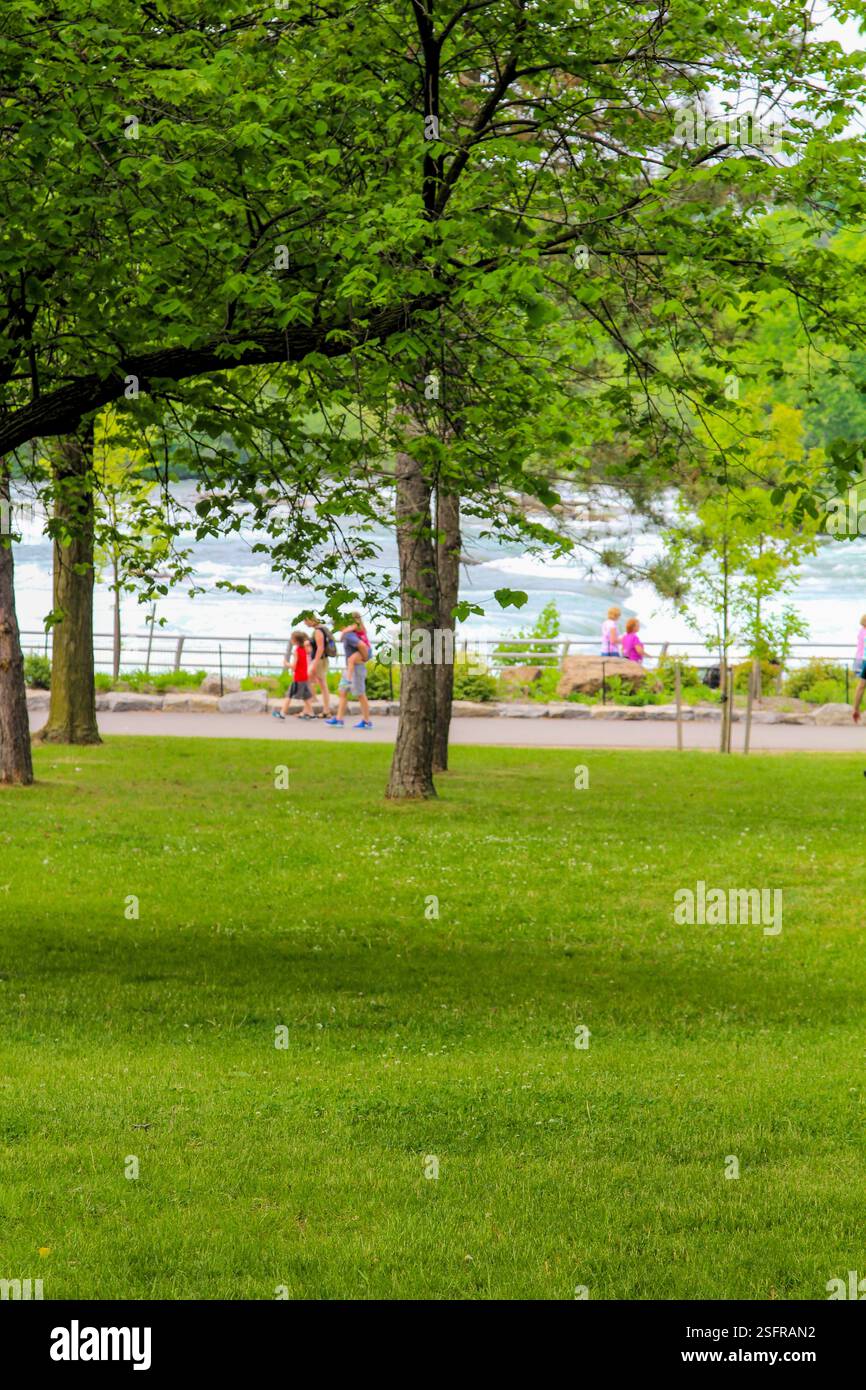 Groups of people stroll along a path by the river in spring Stock Photo ...