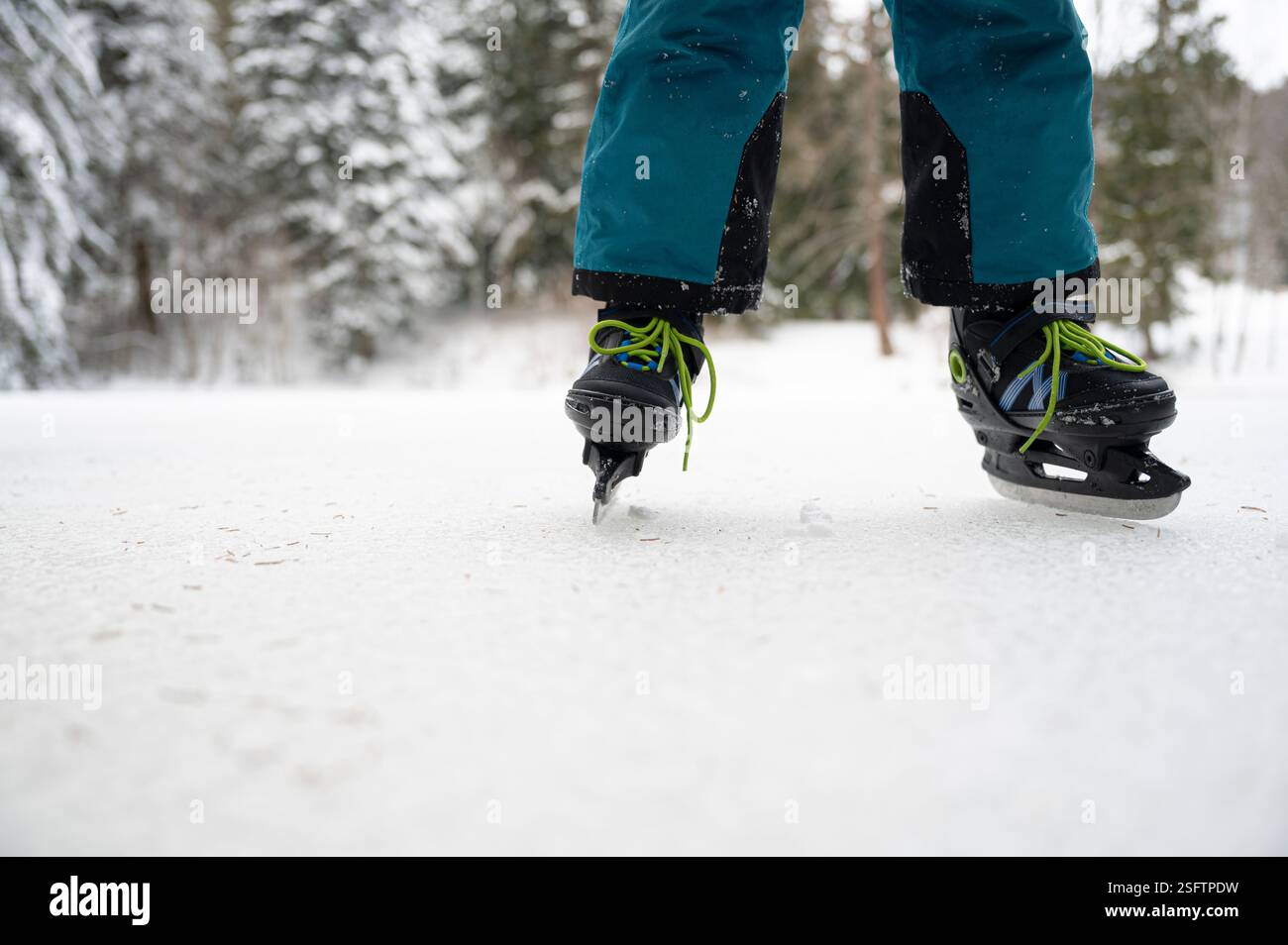 Low angle closeuo view of a childs legs ice skating on a natural ice ...