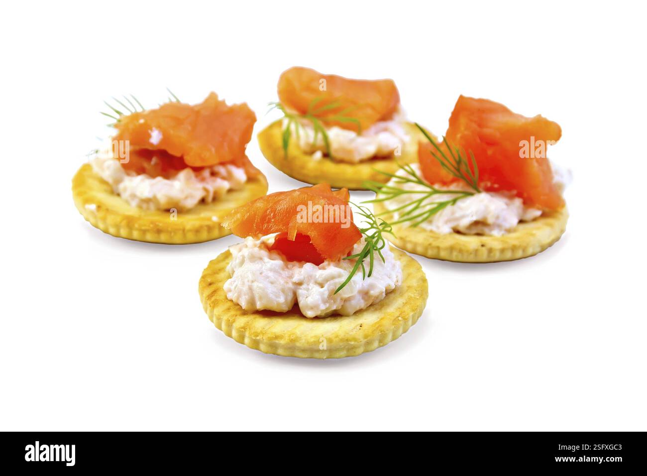 Four round crackers with cream, dill and salmon isolated on white ...