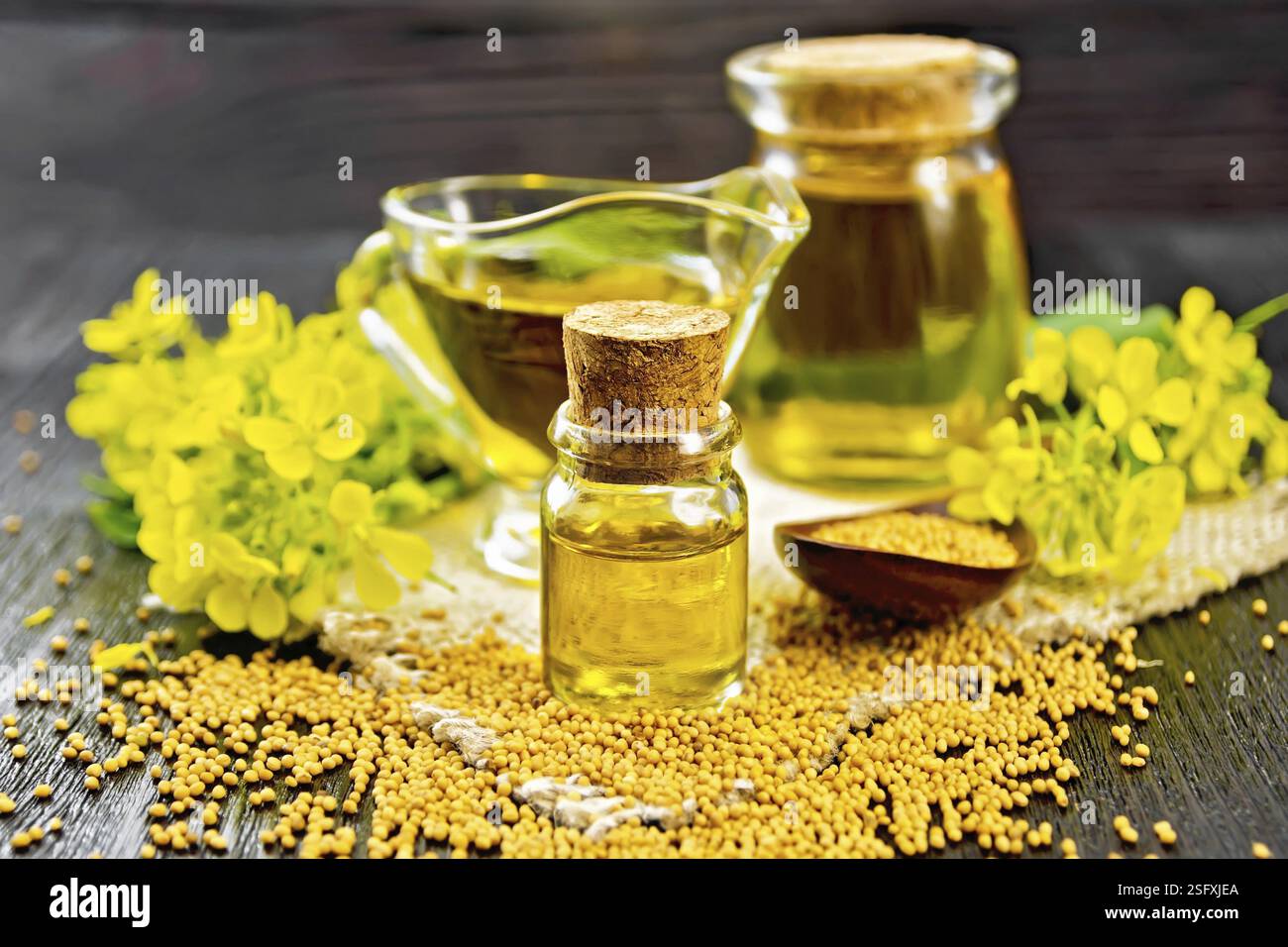Mustard oil in two glass jars and a sauceboat, grains, leaves and ...
