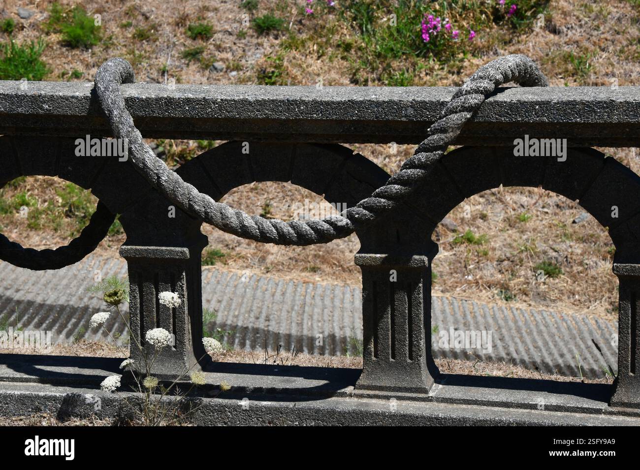 Old weathered fishing rope hangs from bridge's concrete rail Stock ...