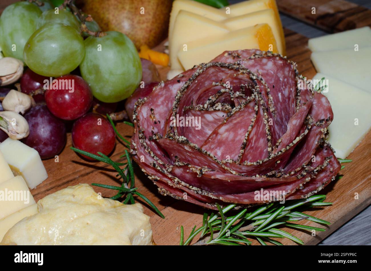 Charcuterie board with delicious meat, cheese and fruit. Beautiful rose ...