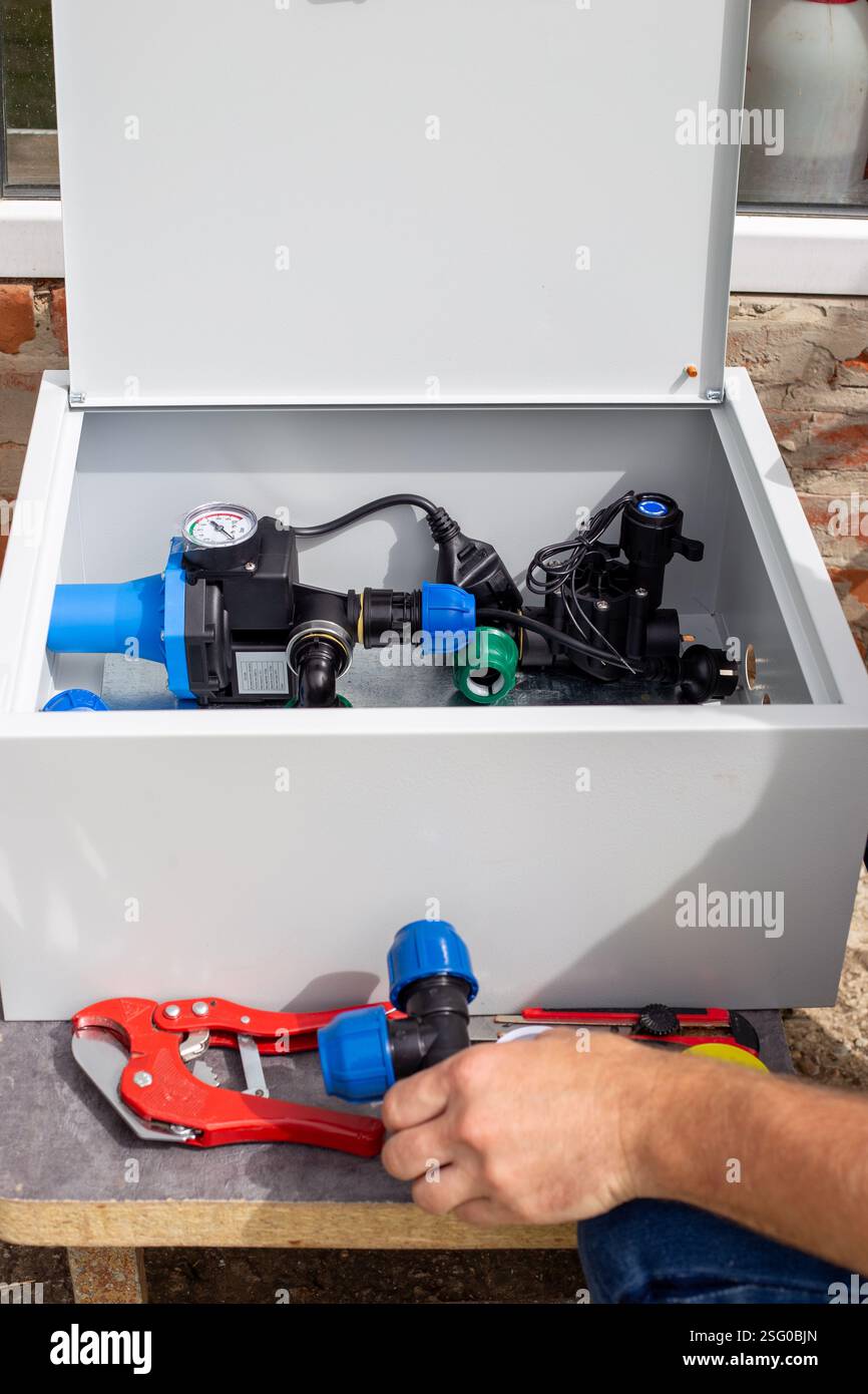 A man assembles a drip irrigation system by arranging the elements of ...