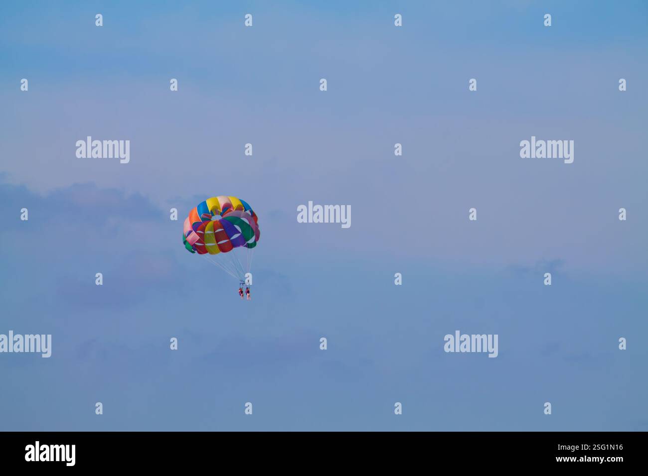 A colorful parachute with two people soaring high in the sky ...