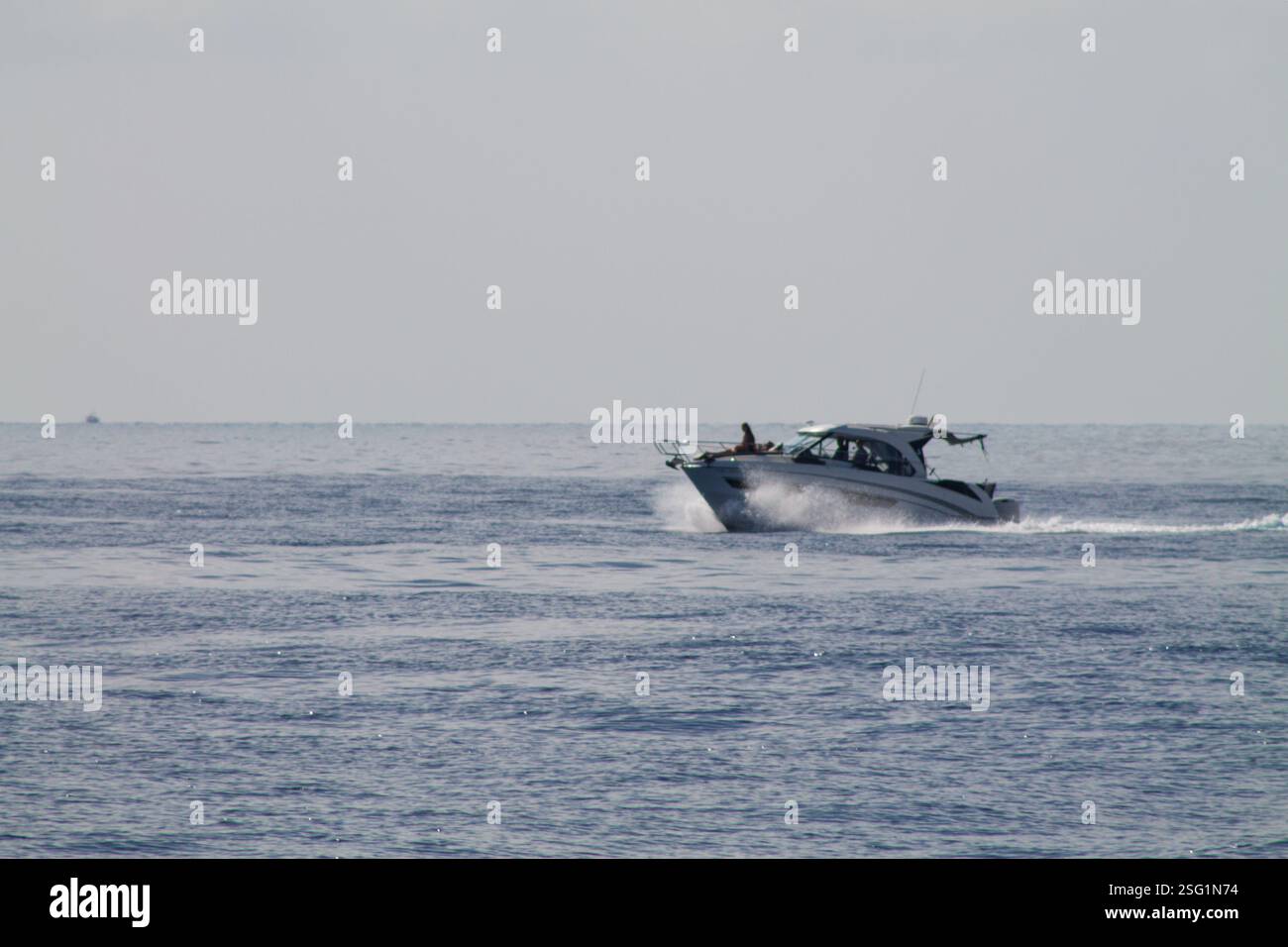 A sleek motorboat cruising on calm ocean waters under a cloudy sky. The ...