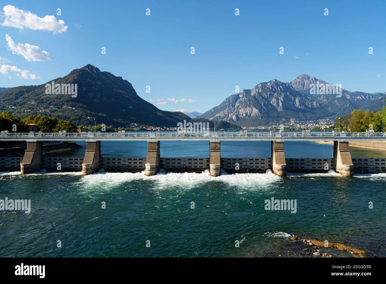 Large dam structure spans across lake with water flowing through the ...