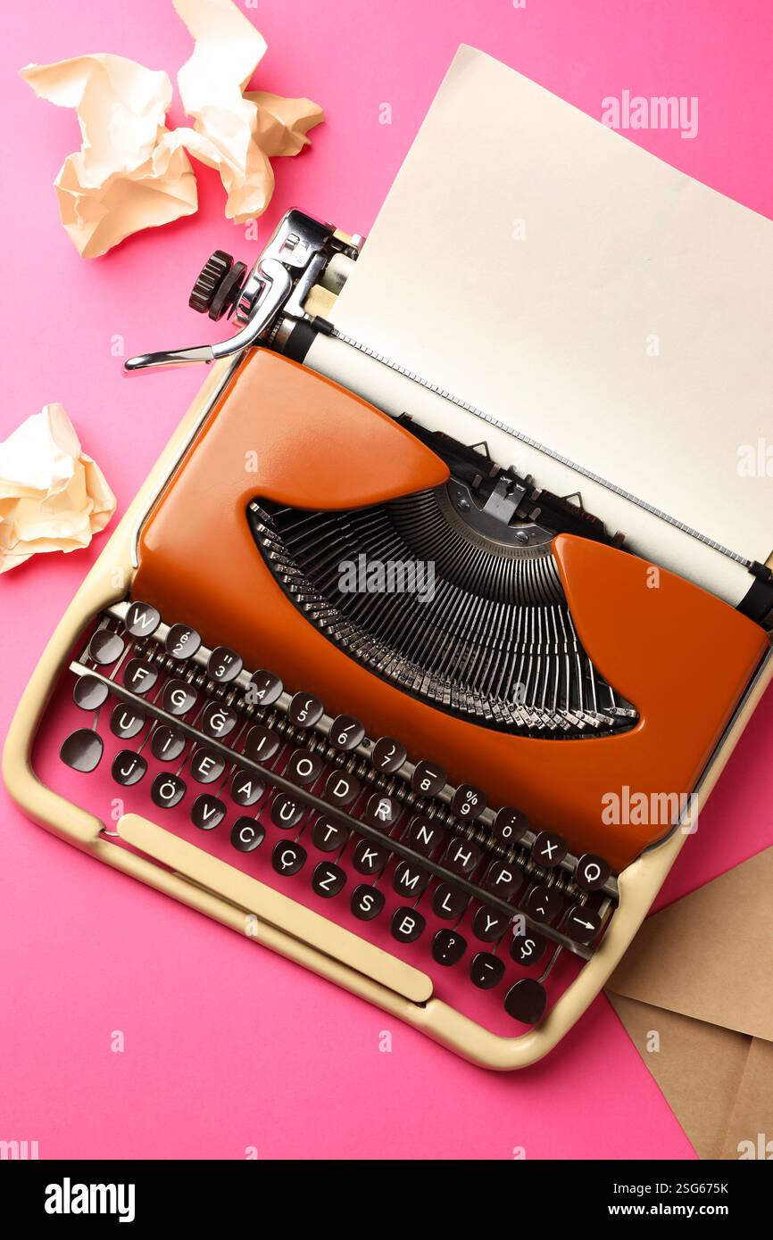 Vintage typewriter, crumpled paper and envelope on pink background ...