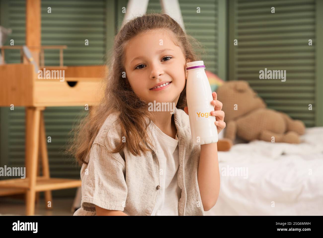 Cute little girl with bottle of yogurt in room Stock Photo - Alamy
