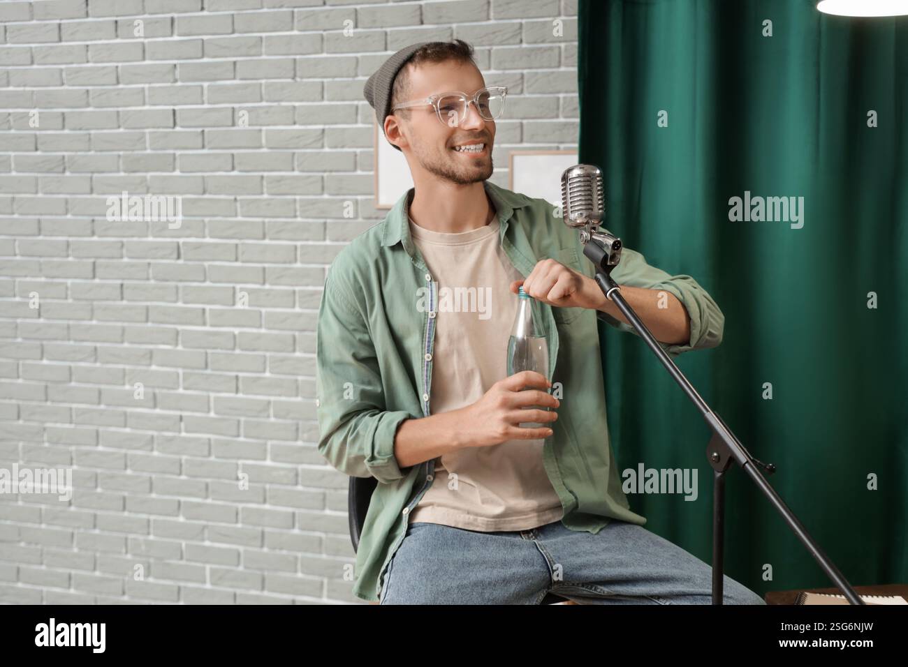 Male standup comedian with water bottle performing on stage Stock Photo ...