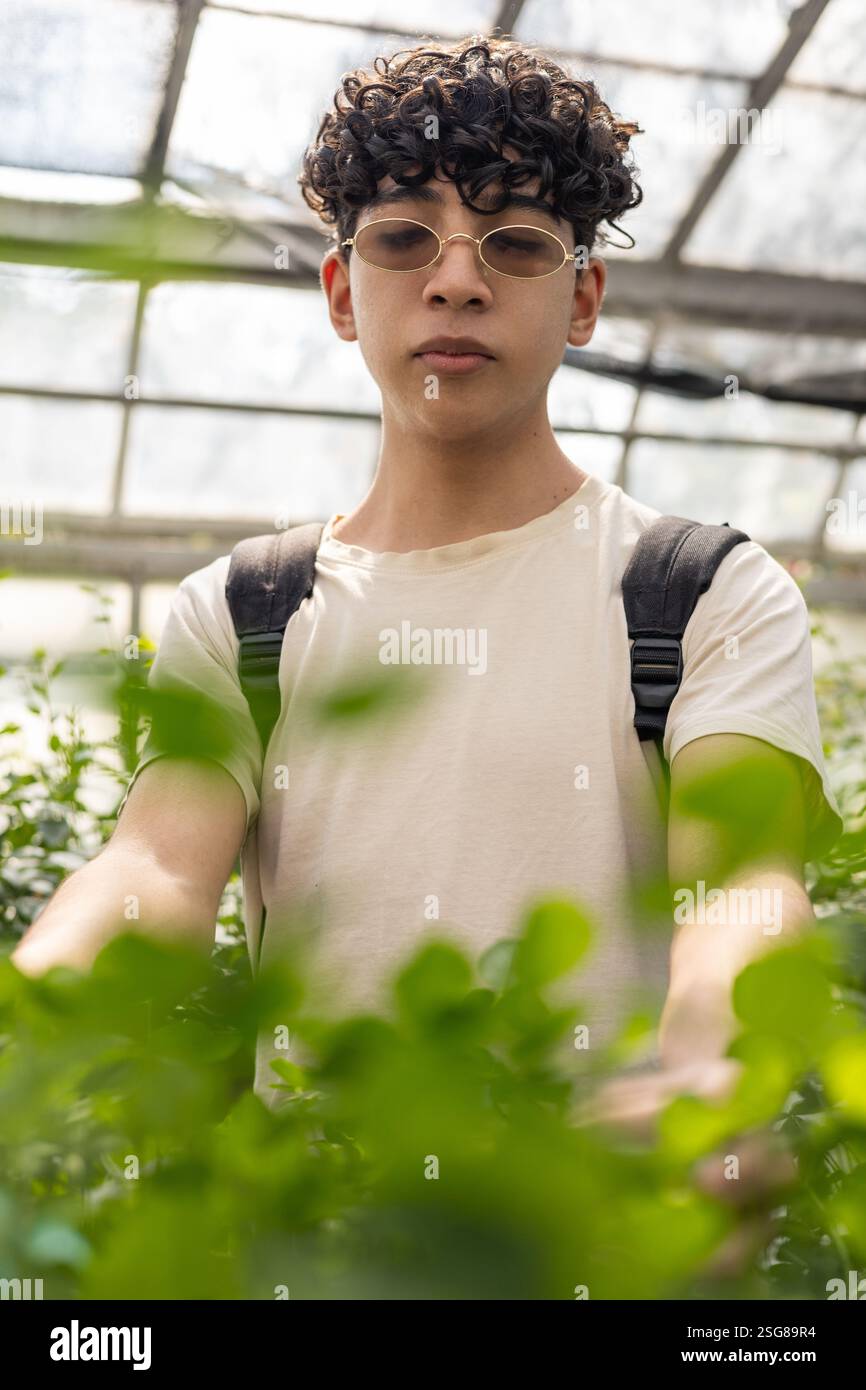 A young person admiring the plants in a nursery, surrounded by greenery ...