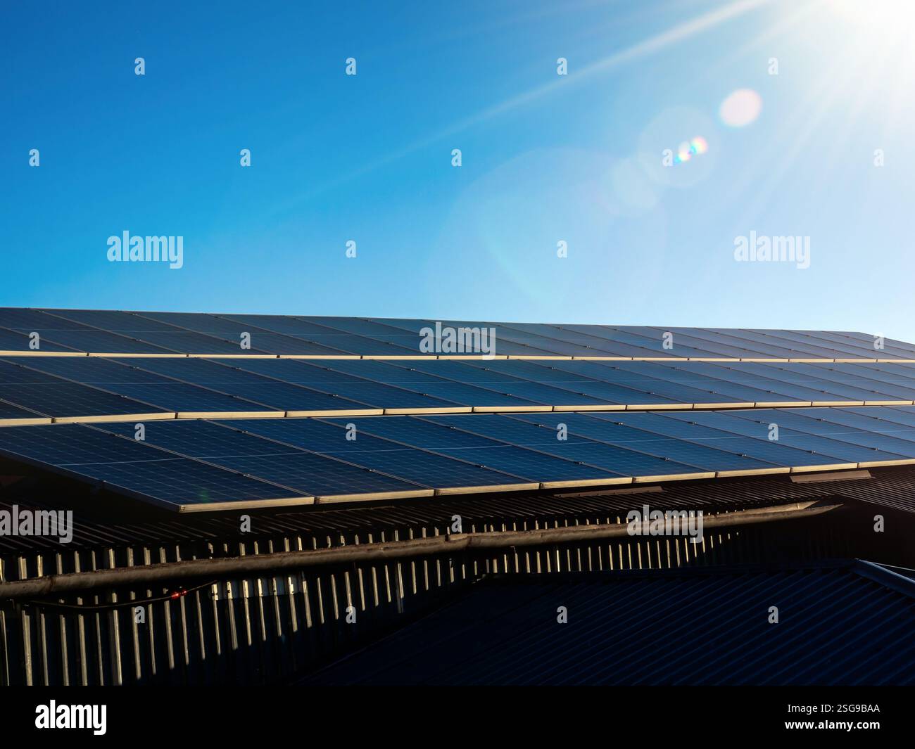 Solar panels on wooden house roof with morning sun rays on blue sky ...