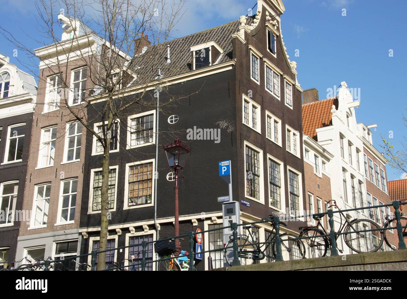 Amsterdam's historic buildings line a peaceful bicycle lane with parked bikes. Dutch ...