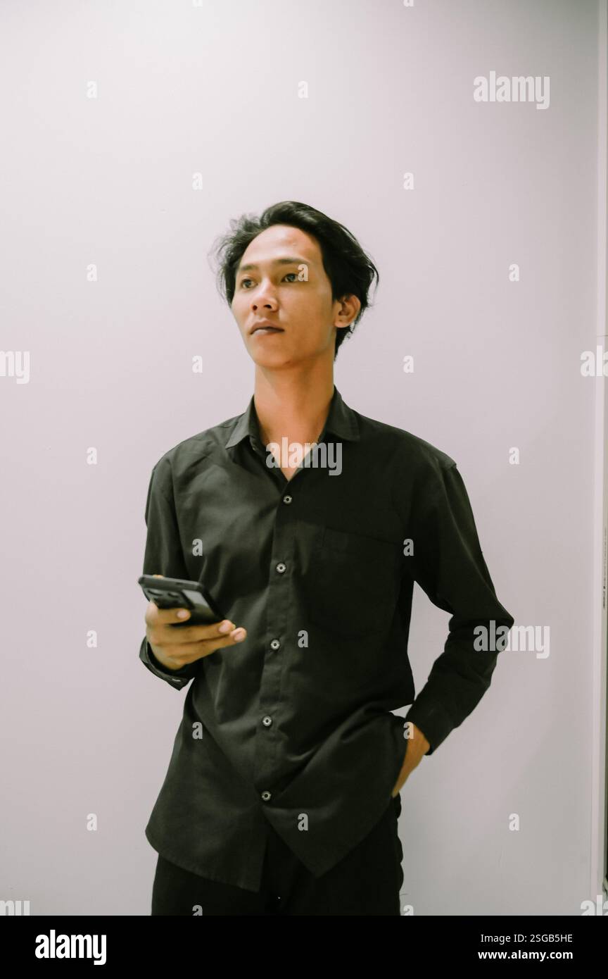 A young man holds his smartphone, ready to connect and communicate ...
