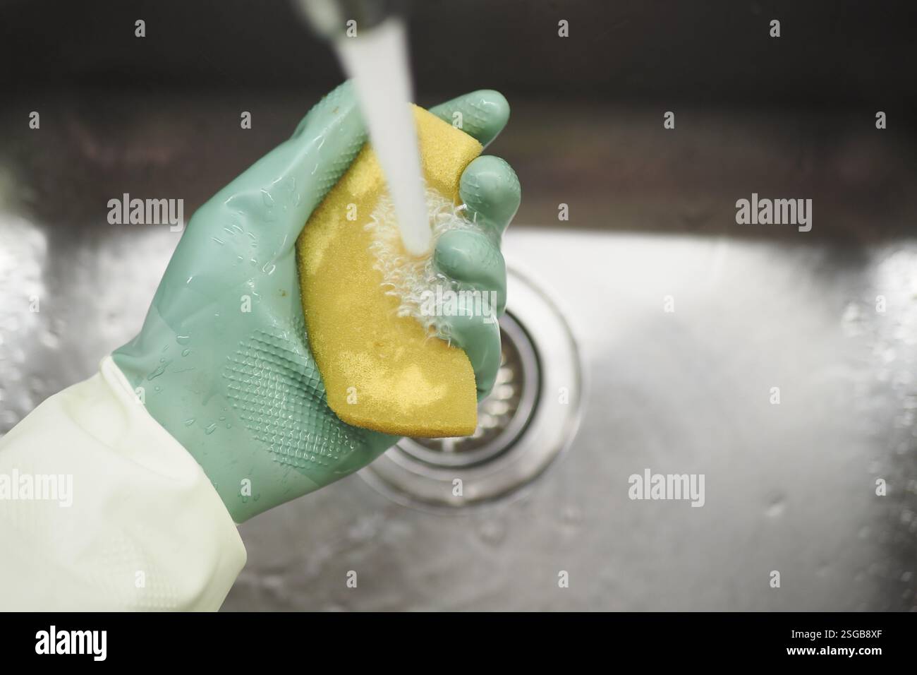 Cleaning sponge under running water in a kitchen sink Stock Photo - Alamy