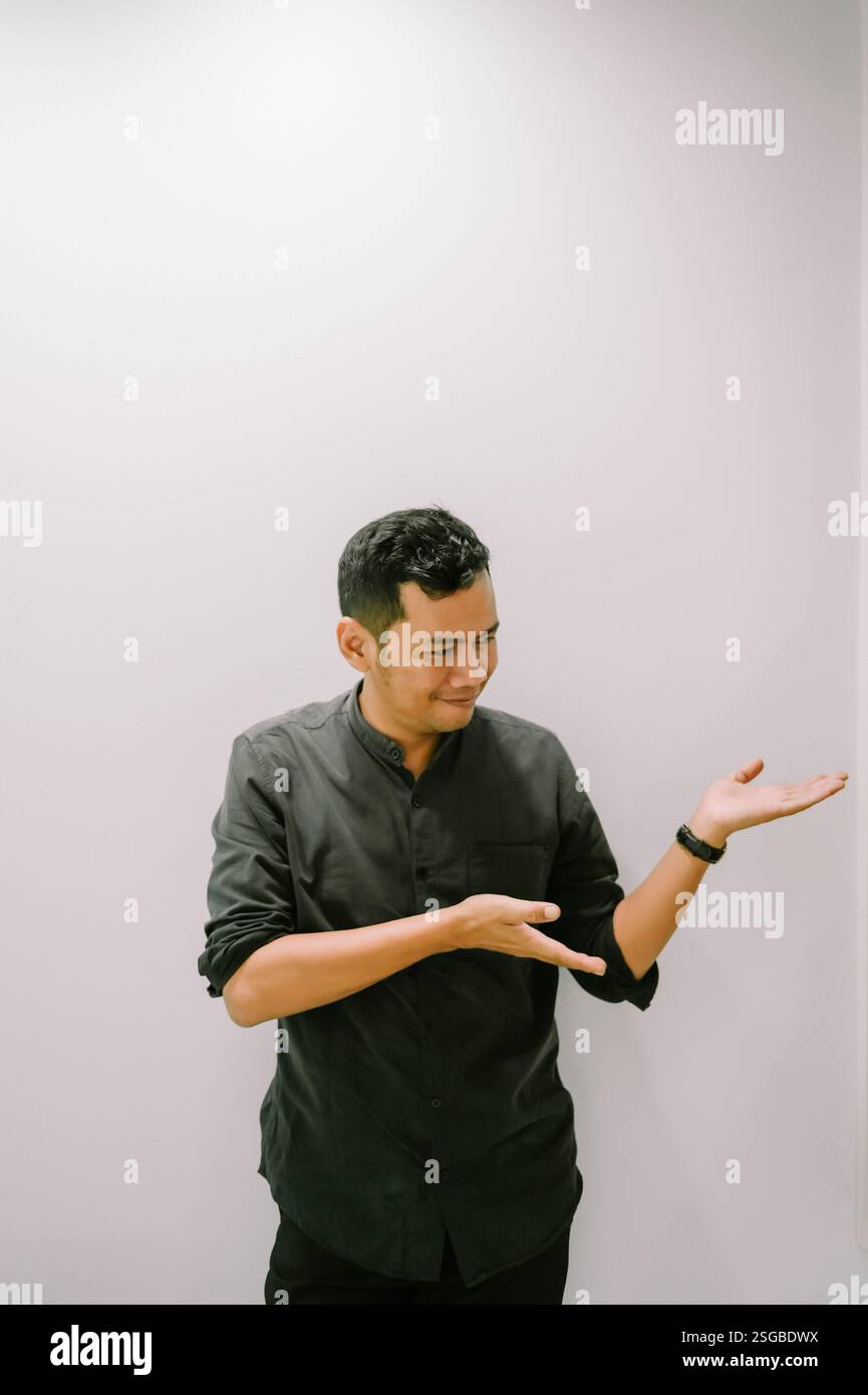 A young man gestures with his hand, presenting or showing something ...