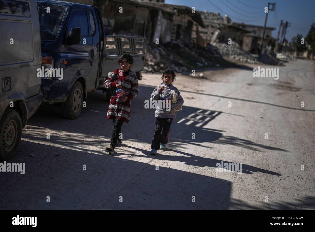 Two girls walk past destroyed homes in the town of Tel Rifaat in the ...