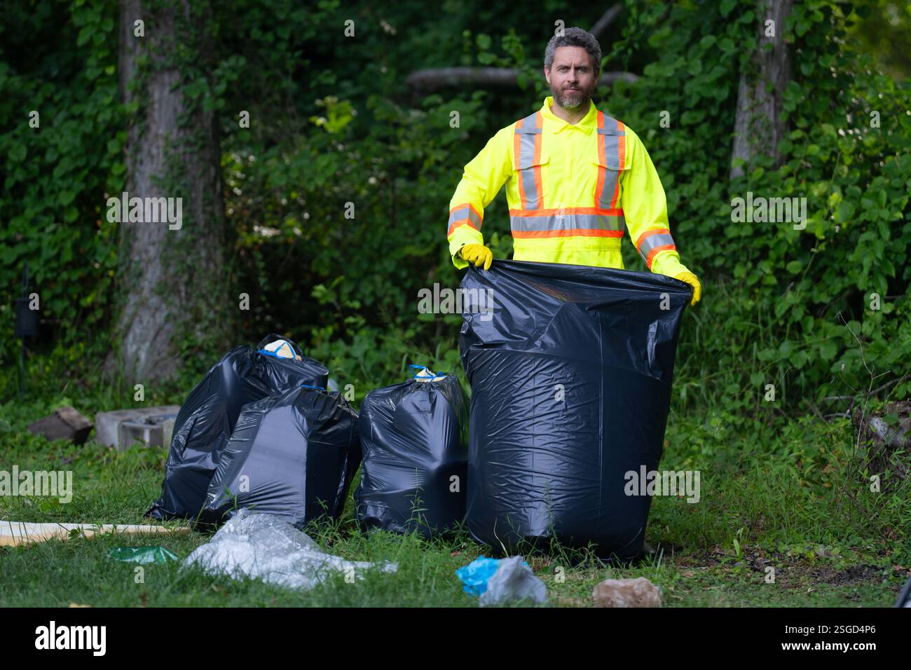Environment plastic pollution. Volunteer collecting trash in the forest and holding a garbage ...