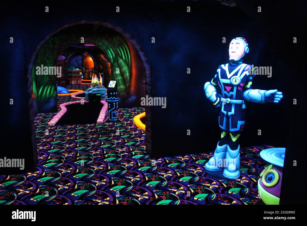 A dark, futuristic tunnel illuminates a glowing robot statue. In ...