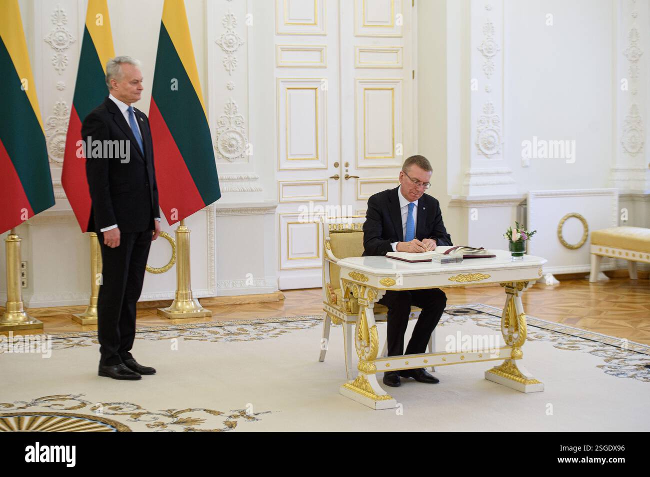 Latvian President Edgars Rinkevics (right) signs the commemorative book ...