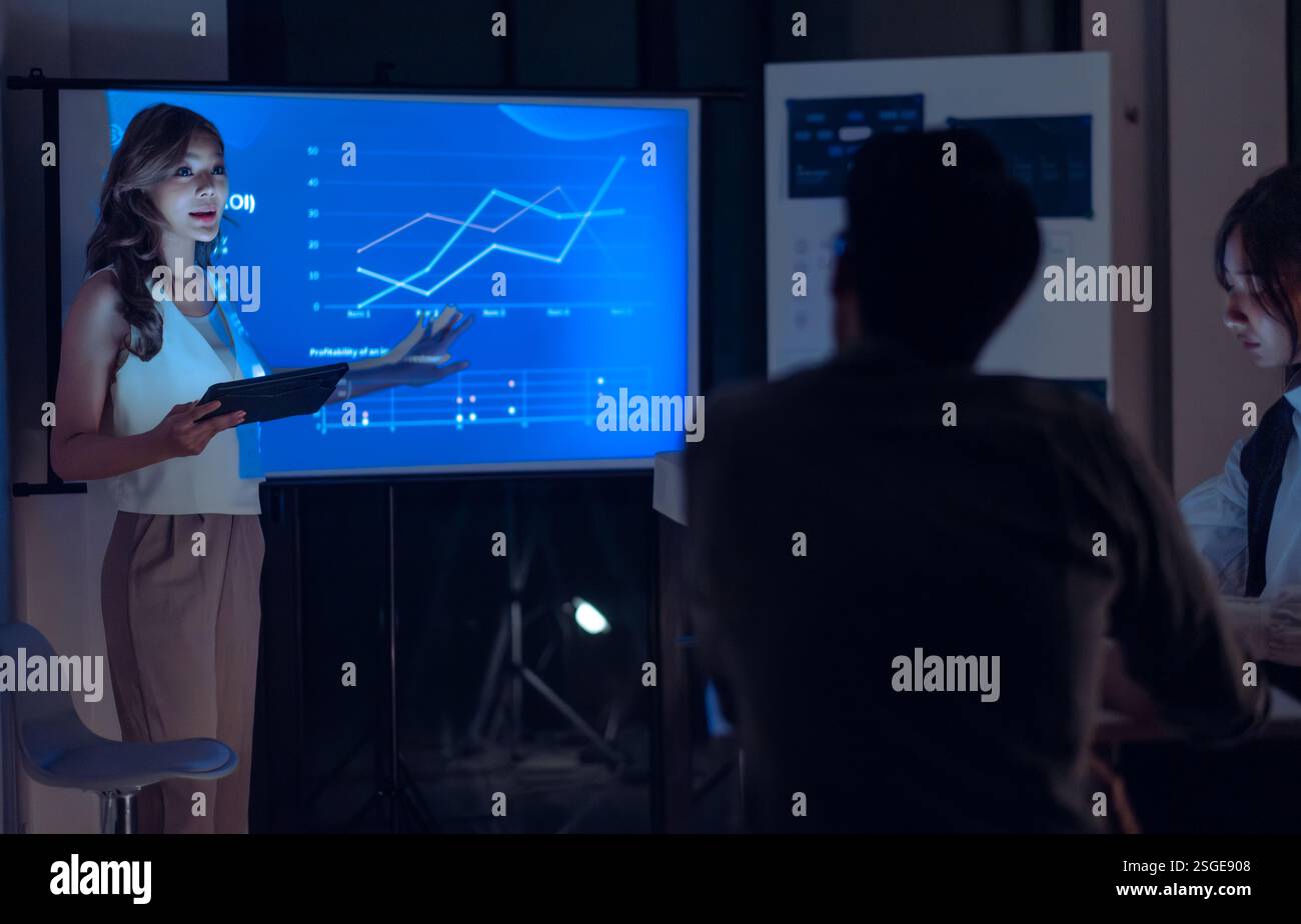 asian leader woman present business presentation in a dimly lit office ...