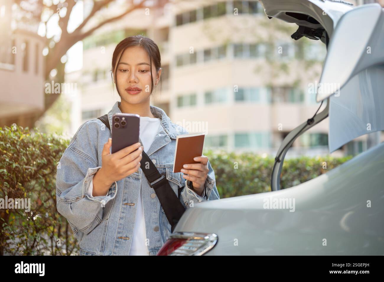 A beautiful, positive Asian woman checks her passport, flight details, and boarding time on her ...