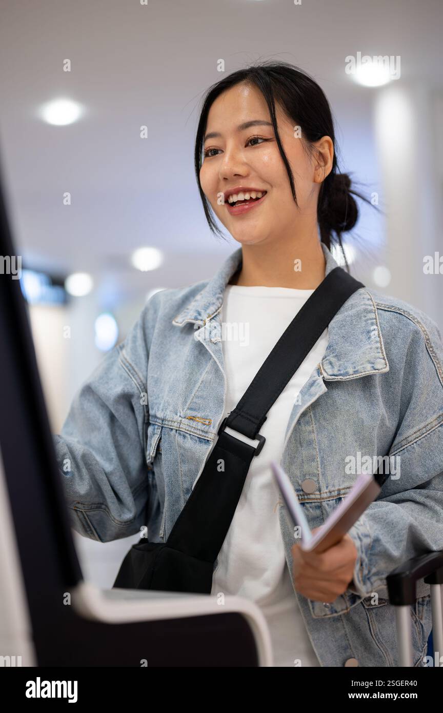 A beautiful, smiling Asian woman is checking in for her flight at an ...