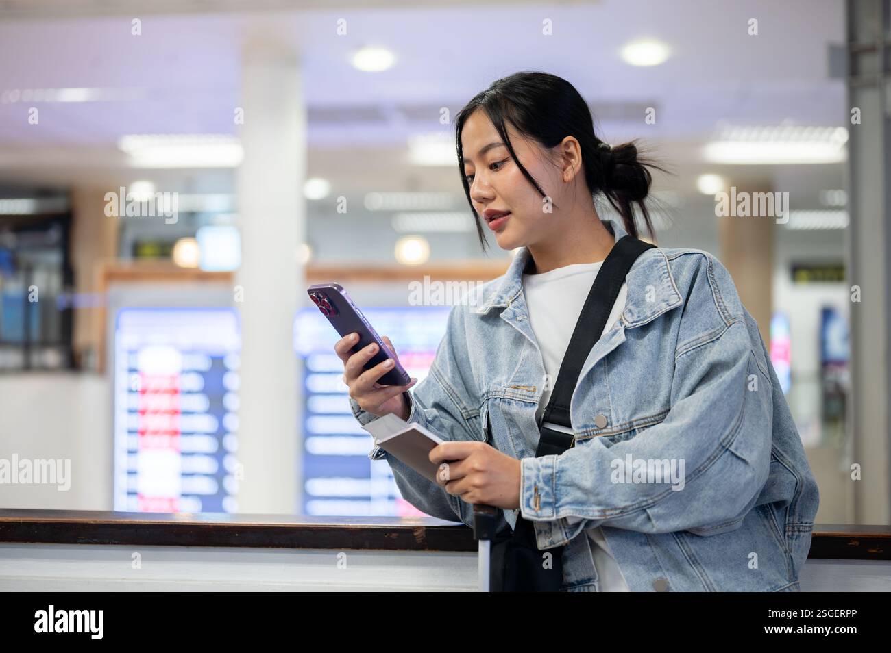 A positive, thoughtful Asian female passenger checks her flight ...