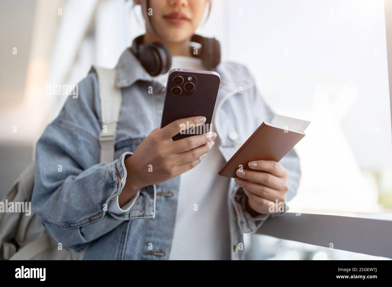 A close-up of an Asian female passenger waiting for her flight boarding time at the airport ...