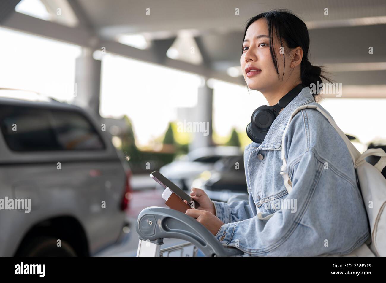 A beautiful, positive Asian female traveler stands at the airport taxi ...