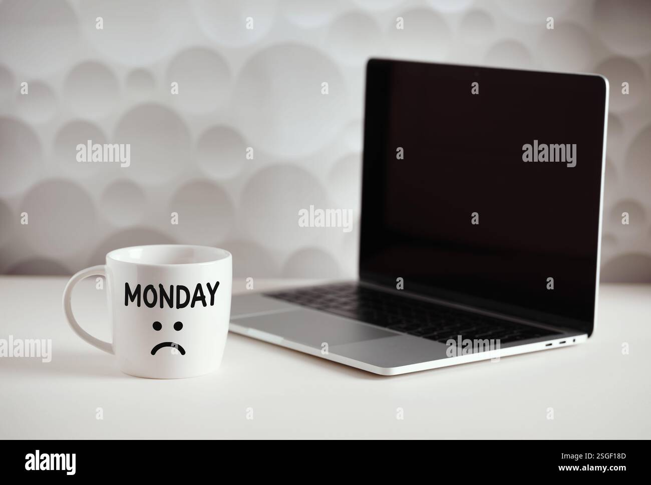 White mug with Monday writing and sad face next to laptop on white ...