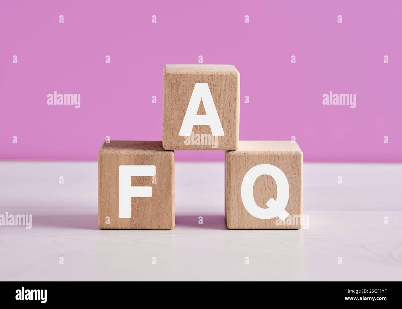 Three wooden cubes with white letters forming the acronym FAQ ...