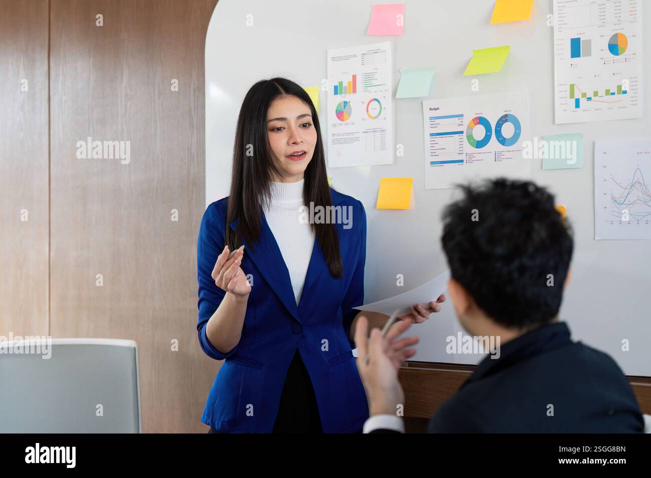 Businesswoman leading a team presentation with visual aids, promoting ...