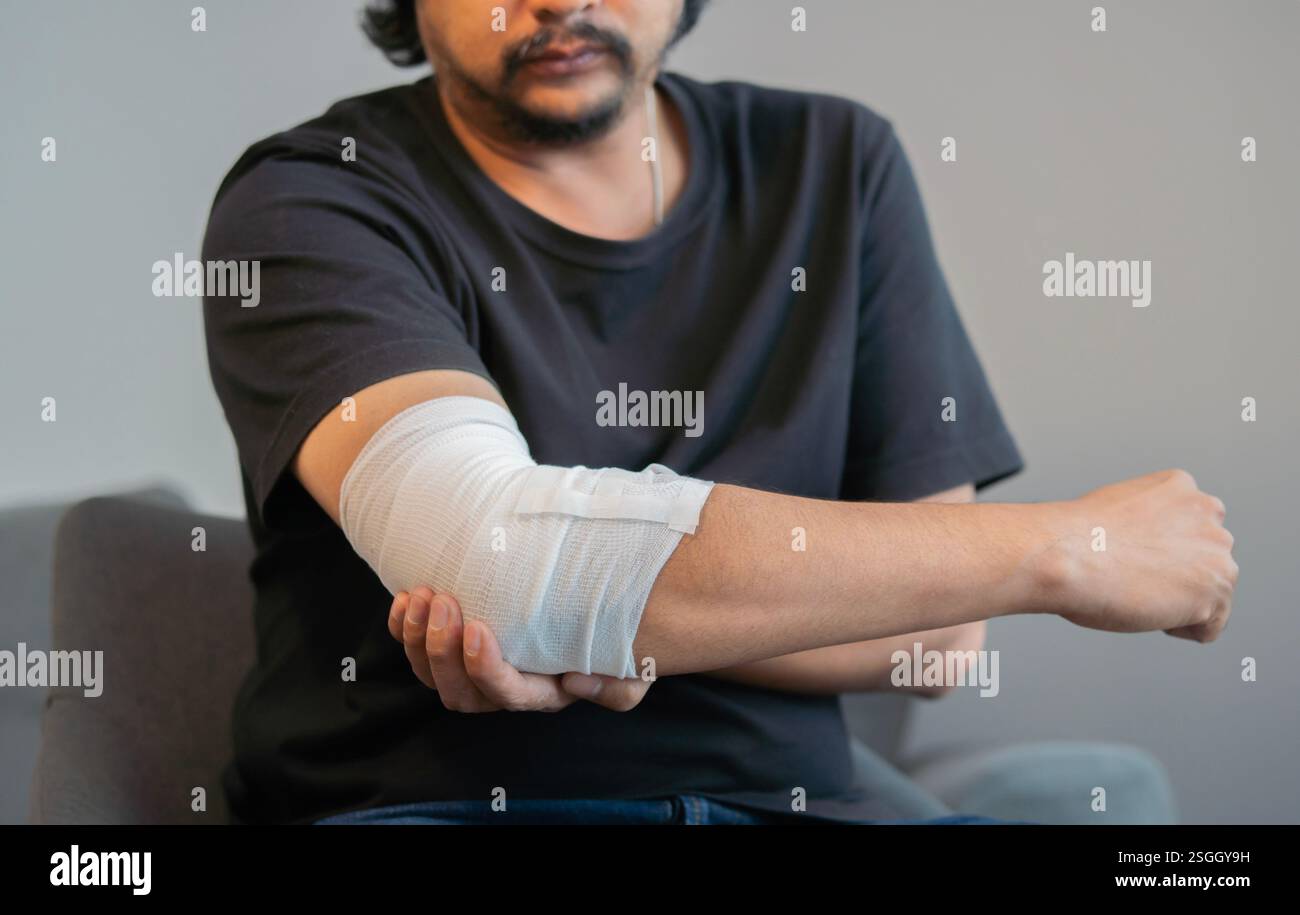 A man with painful elbow due to overuse or sport accidental. He hold ...