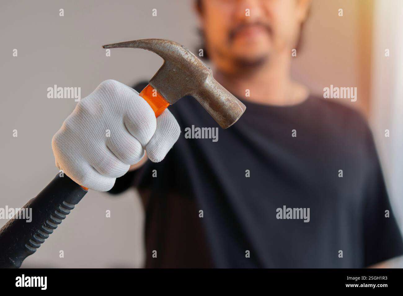 A young man's hand wear white cloth gloves and holding old hammer for ...