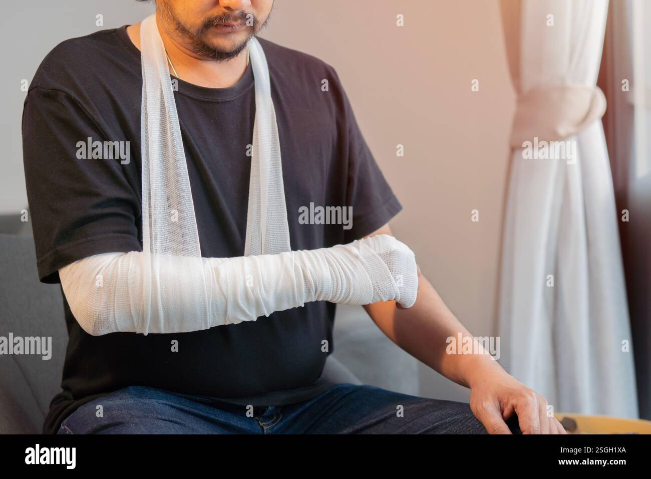 Beard Asian man sit at home with a wounded elbow covered with white ...