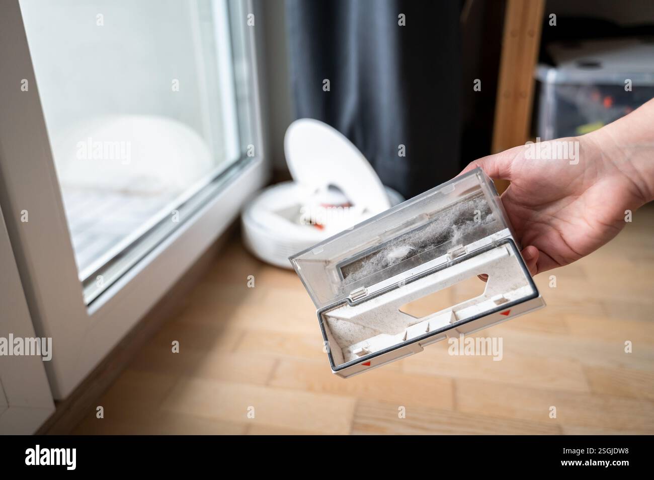 Hand holds full dustbin from robot vacuum, ready for cleaning, with ...