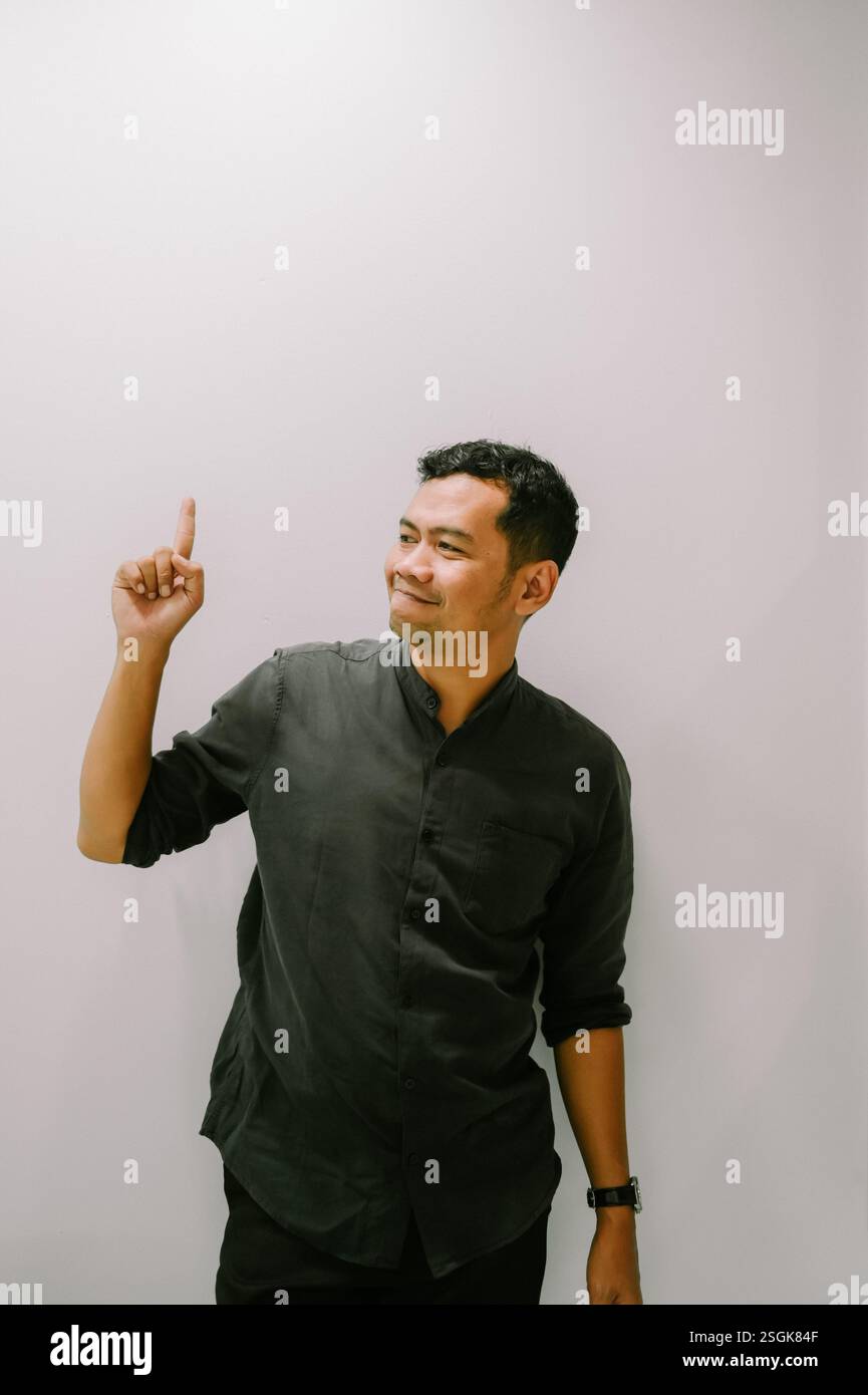 A young man points upwards, directing attention to something above ...