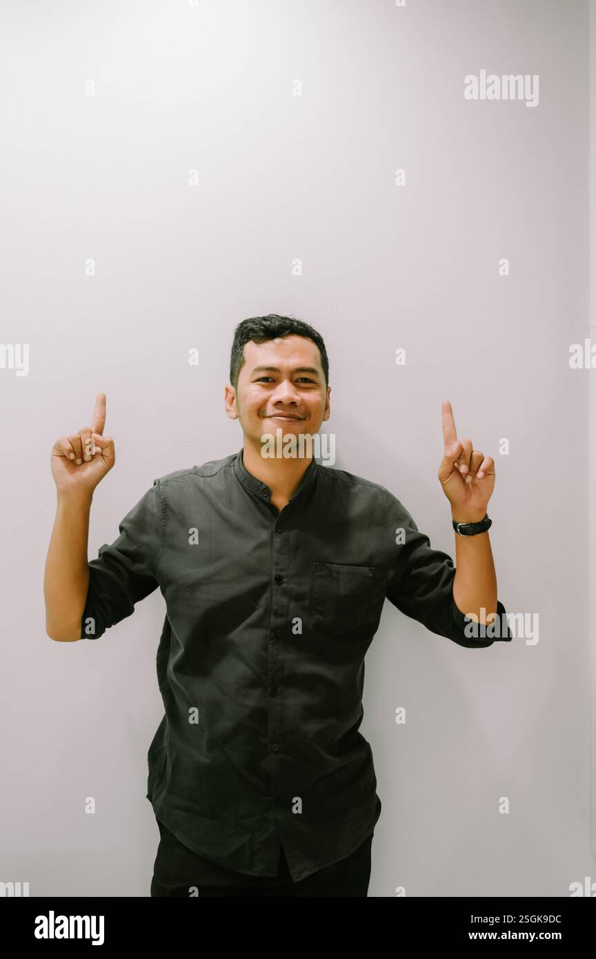 A young man points upwards, directing attention to something above ...