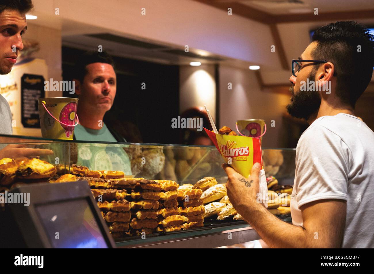 Men eating churros on the street Stock Photo - Alamy