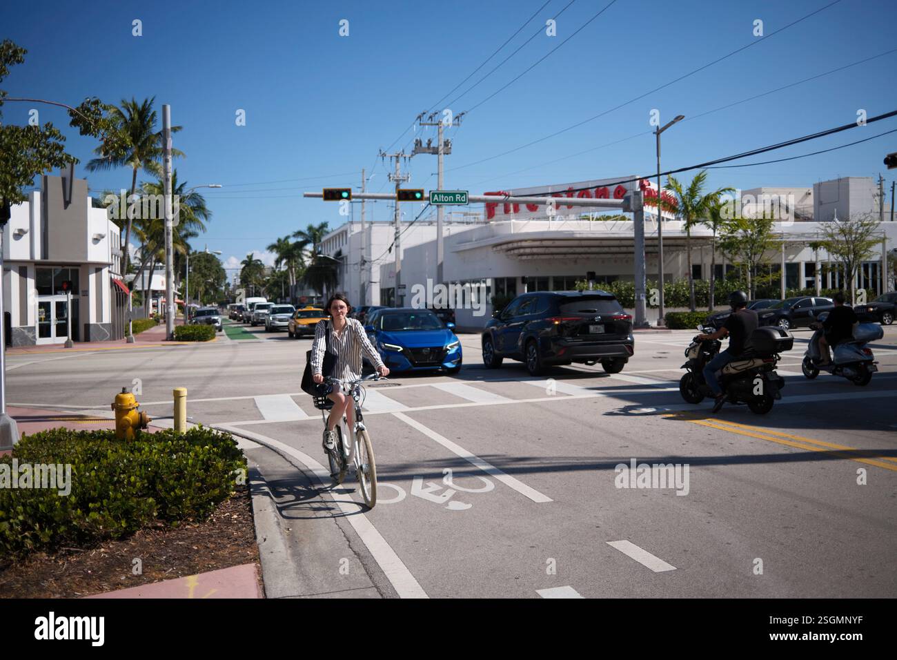 Urban street scene with a cyclist, cars, and palm trees under a clear ...