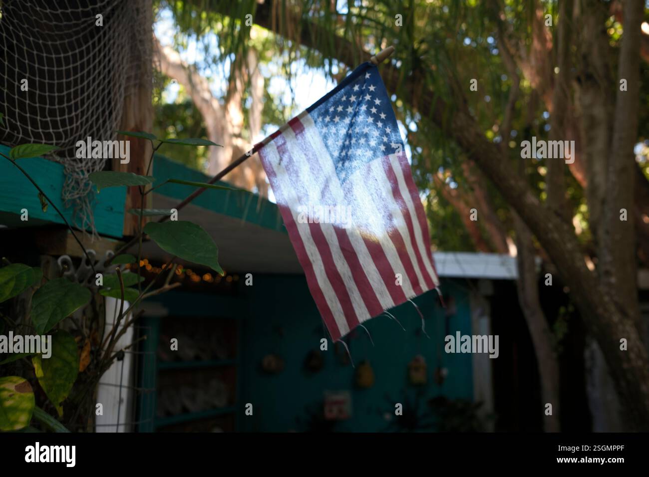 An American flag hangs in a lush, tree-filled outdoor setting, with ...