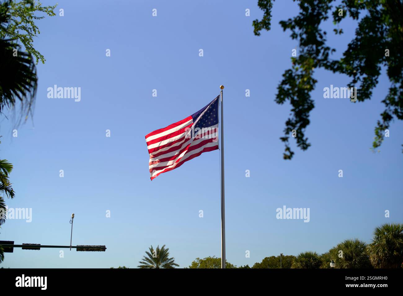 American flag waving on a tall flagpole against a clear blue sky with ...
