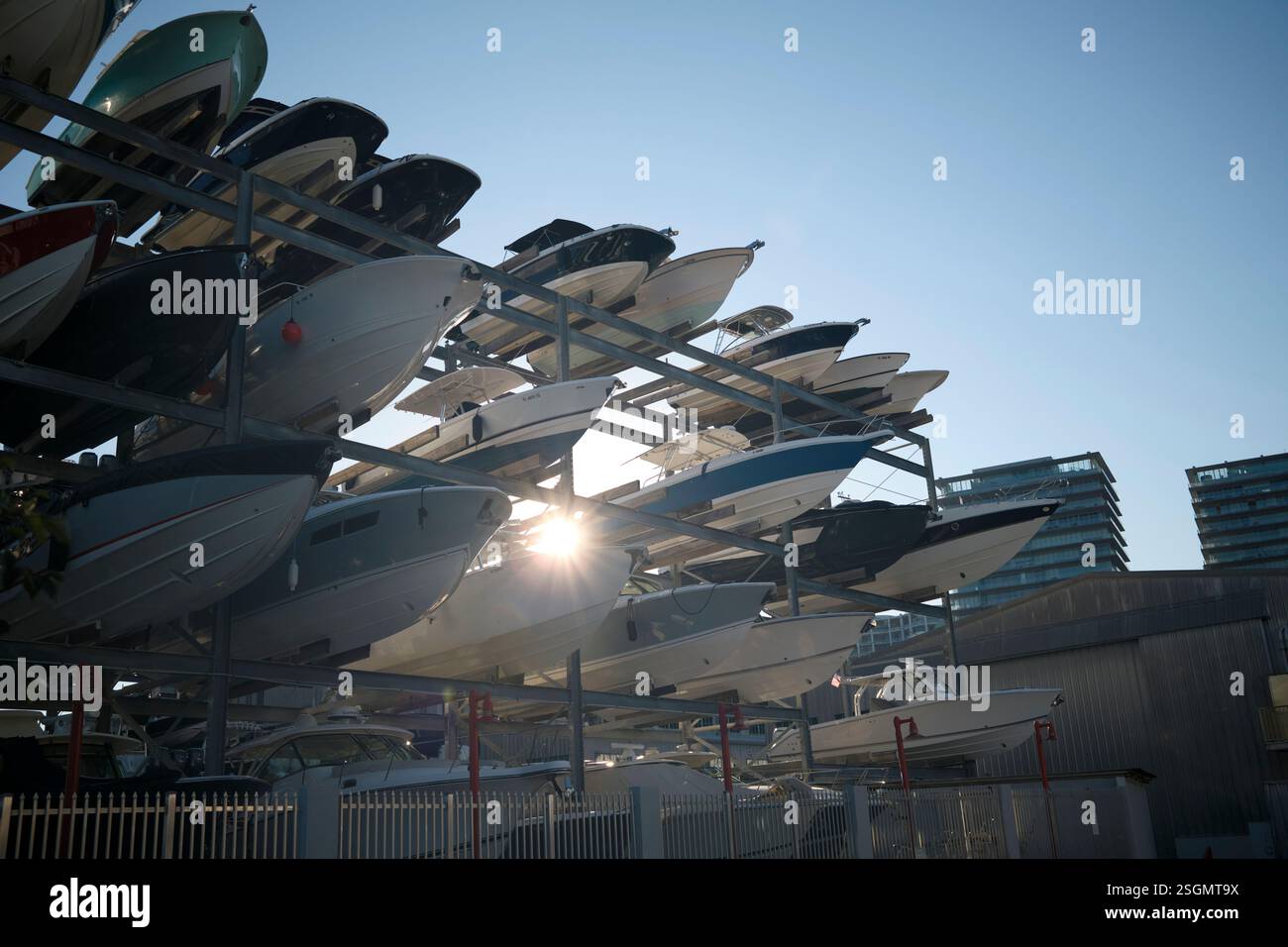 Stacked motorboats on metal racks with sunlight shining through in a ...